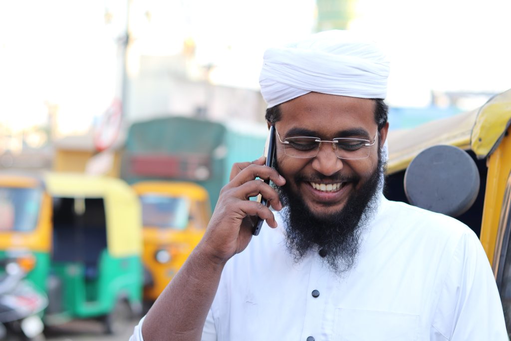 Indian muslim boy man talking on phone looking down and laughing ...